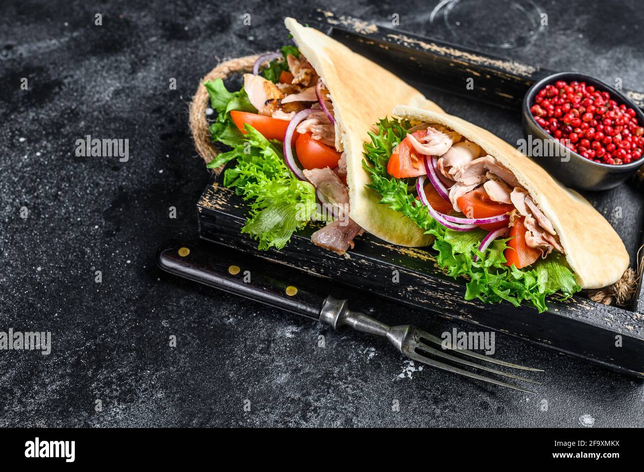 Doner kebab with grilled chicken meat and vegetables in pita bread on a ...