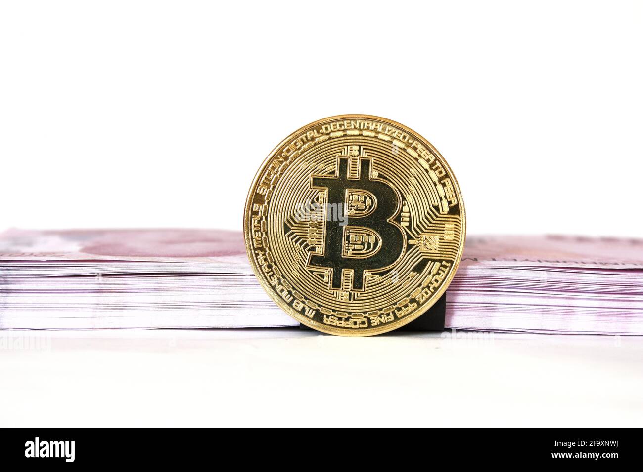Gold color bitcoin in front of stack of money banknotes isolated on ...