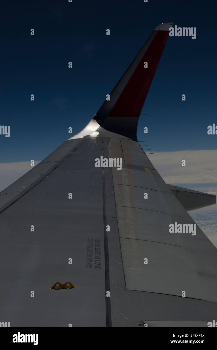 full wing of an airplane flying, with cloud mattress in the background ...