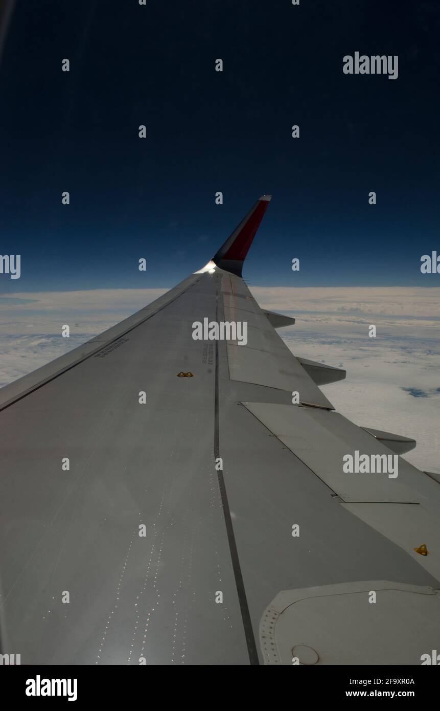 full wing of an airplane flying, with cloud mattress in the background ...