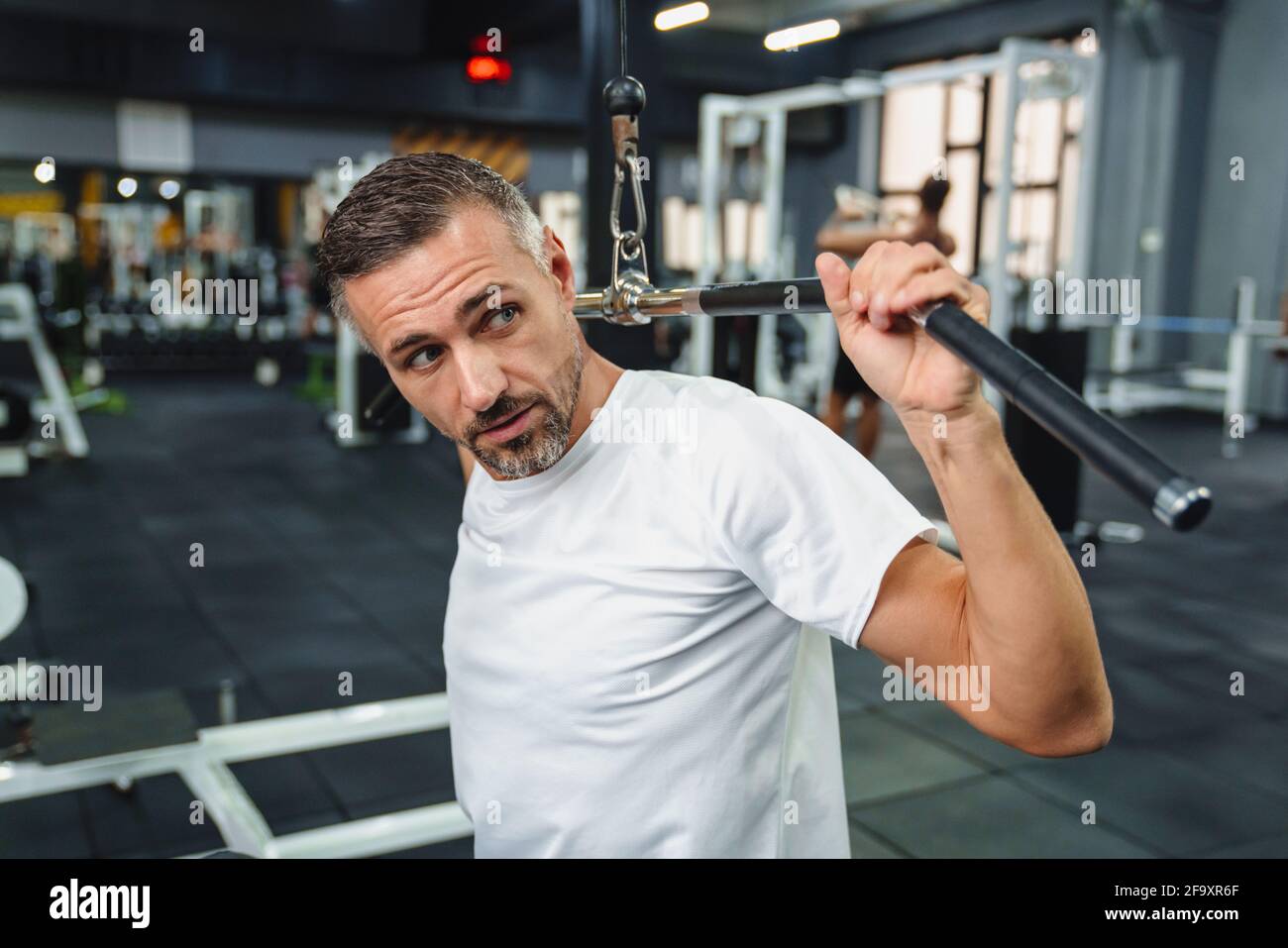 Attractive confident healthy sports man using seated lat pulldown ...