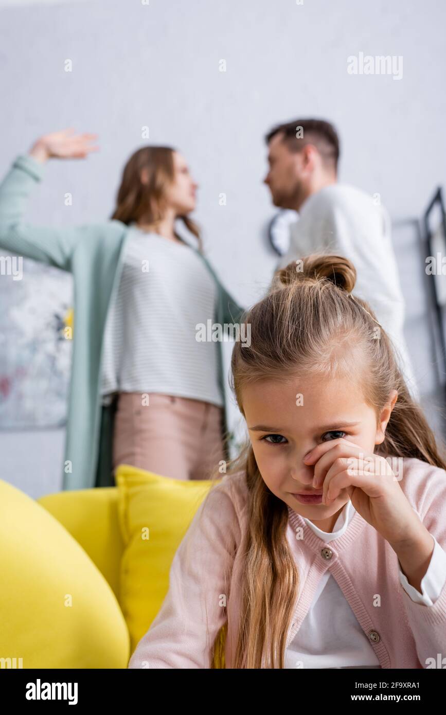 Crying kid sitting near blurred parents quarrelling Stock Photo - Alamy