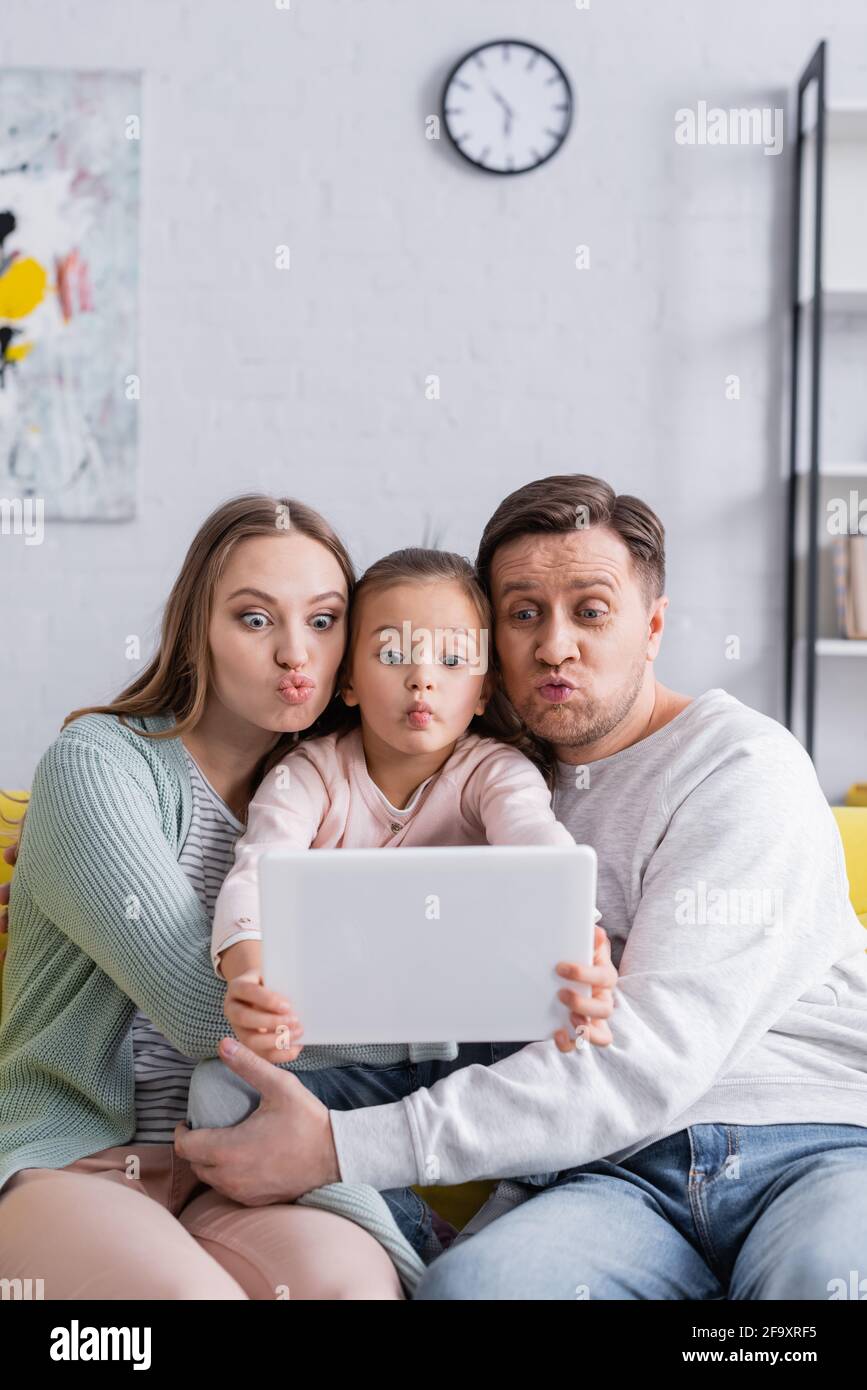 Family pouting lips while taking selfie on digital tablet on blurred ...