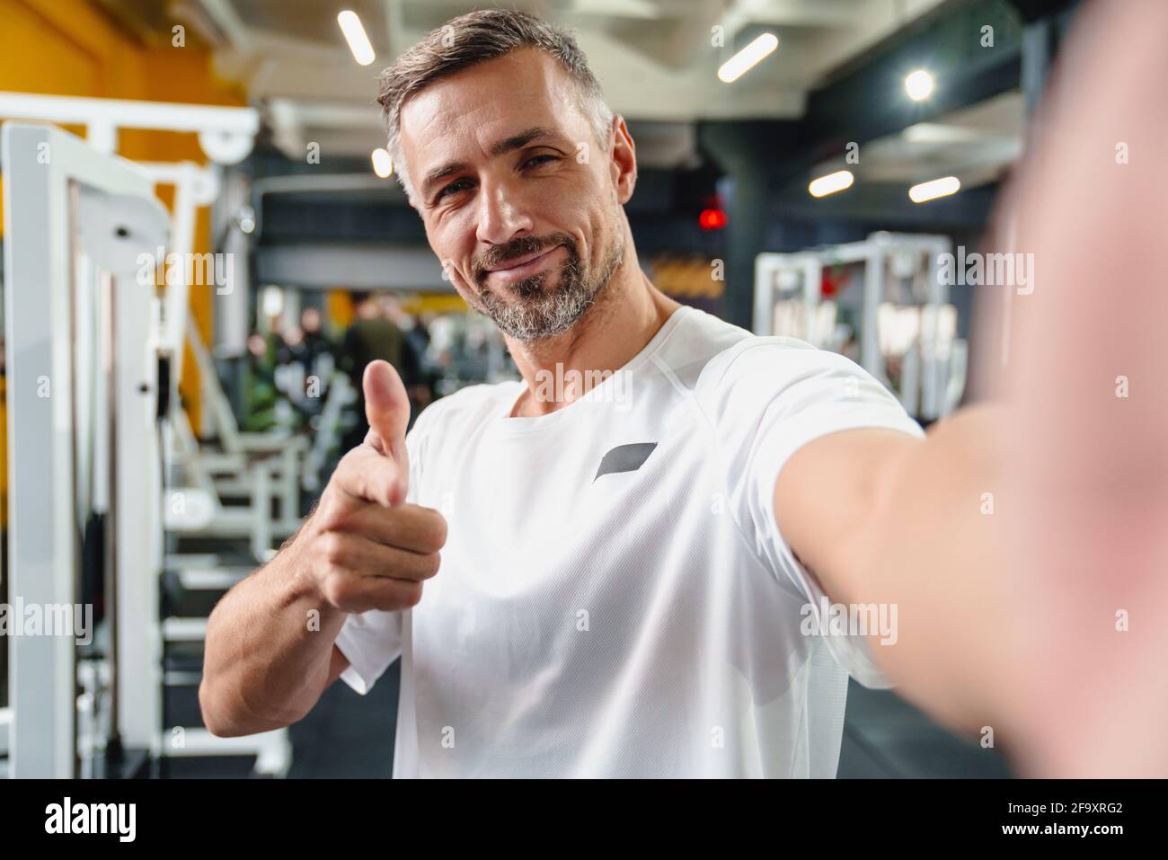 Joyful grey adult sportsman pointing finger at camera while taking ...