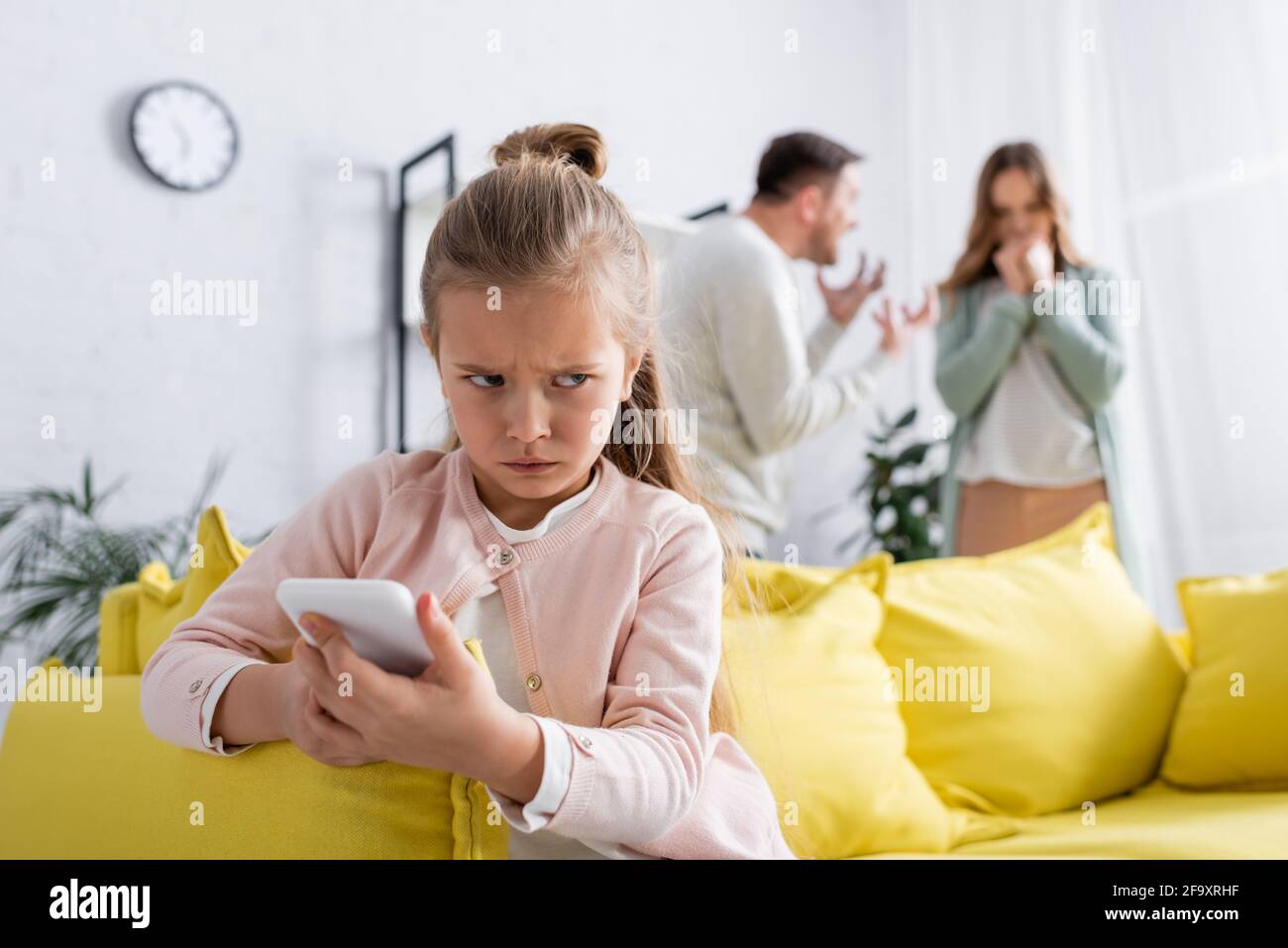 Sad kid using smartphone while parents quarrelling on blurred ...