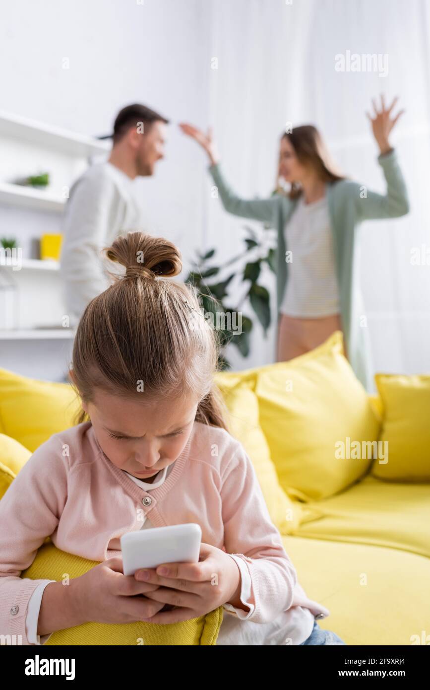 Child using smartphone while parents quarrelling at home Stock Photo ...