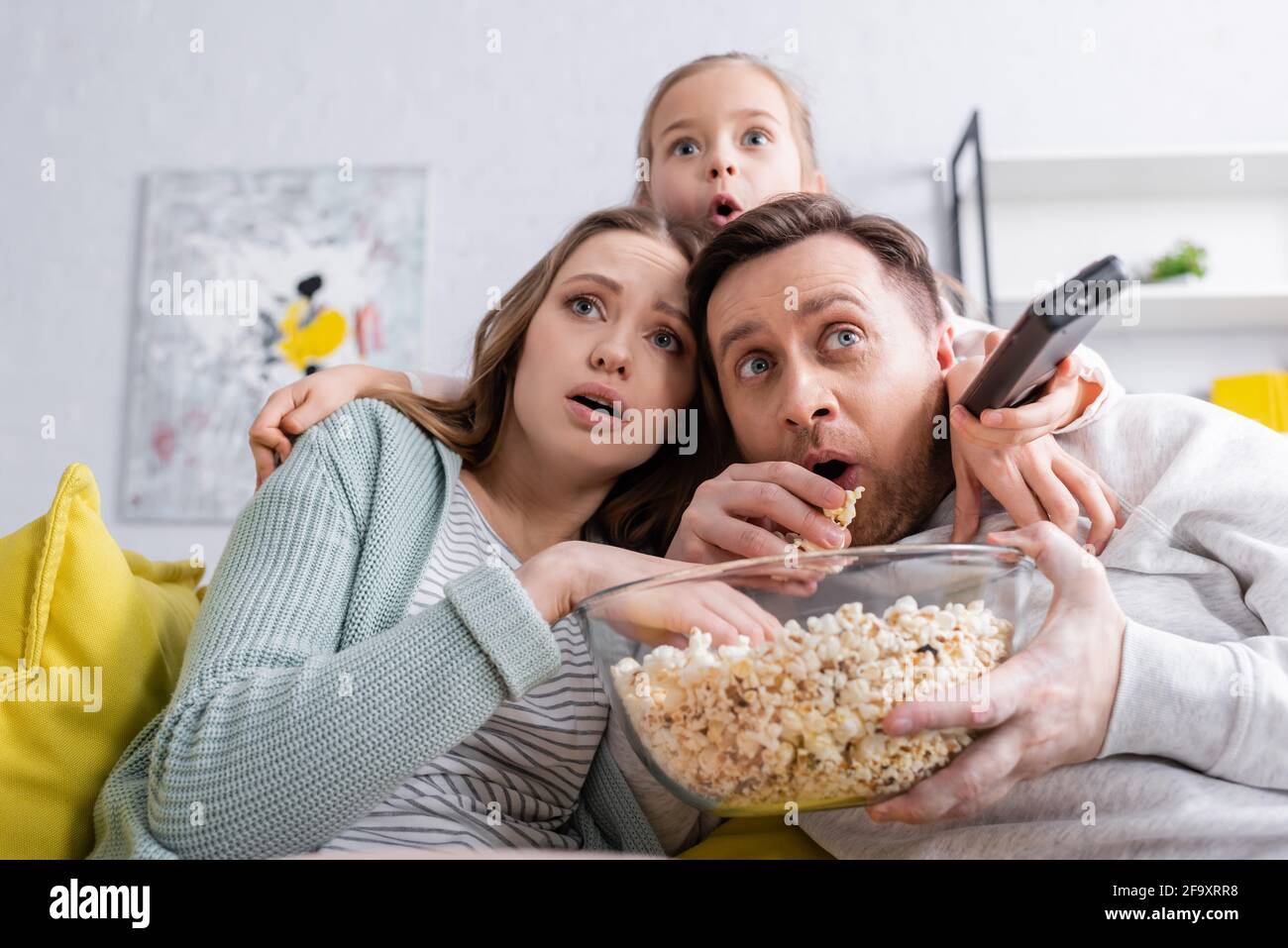 Scared family with popcorn watching film on couch Stock Photo - Alamy