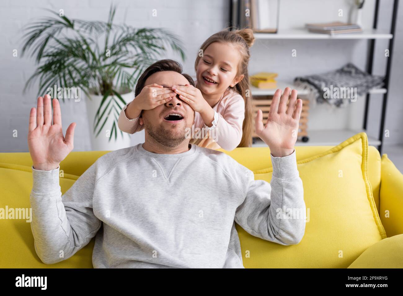 Smiling kid covering eyes of father at home Stock Photo - Alamy