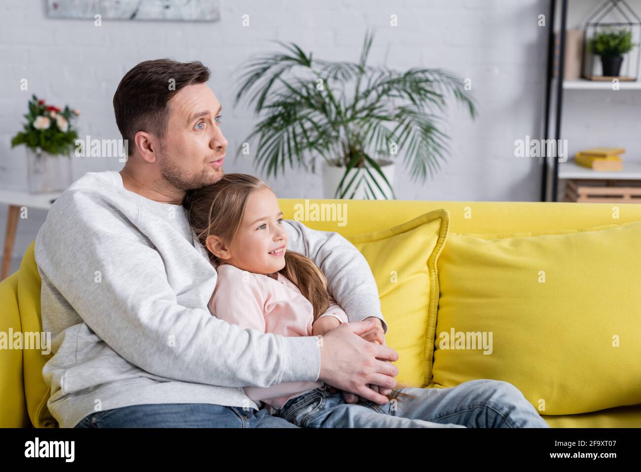 Man talking while hugging smiling child on couch Stock Photo - Alamy