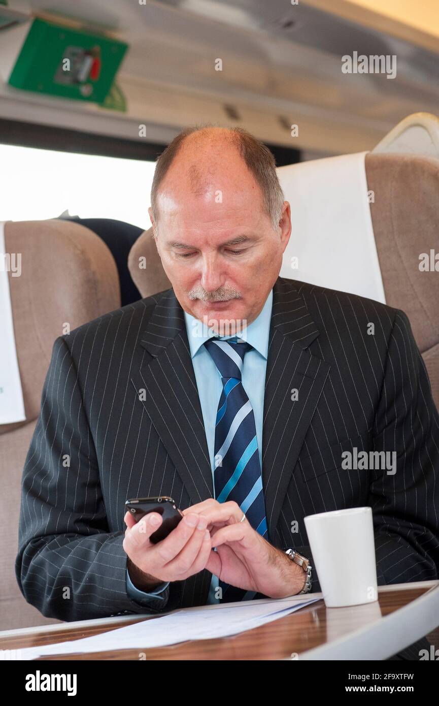 Business man using a mobile phone whilst travelling on a train in the ...