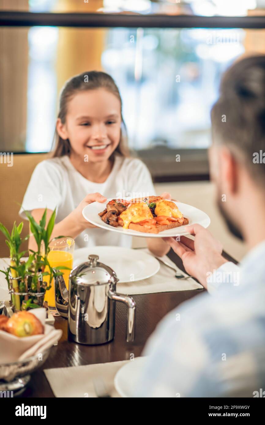 Pretty teen girl taking a plate with food from her dads hands Stock ...