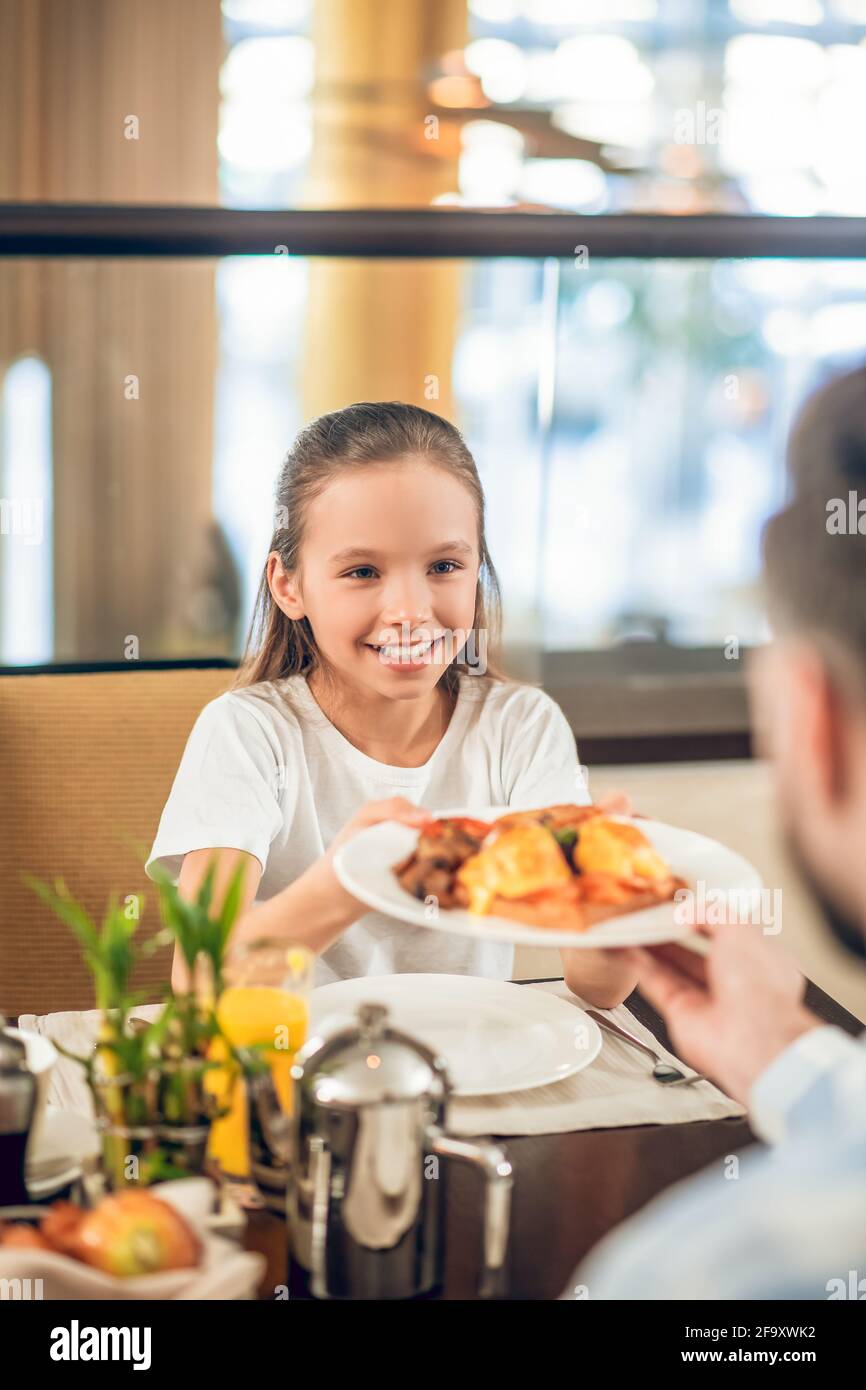 Pretty teen girl taking a plate with food from her dads hands Stock ...