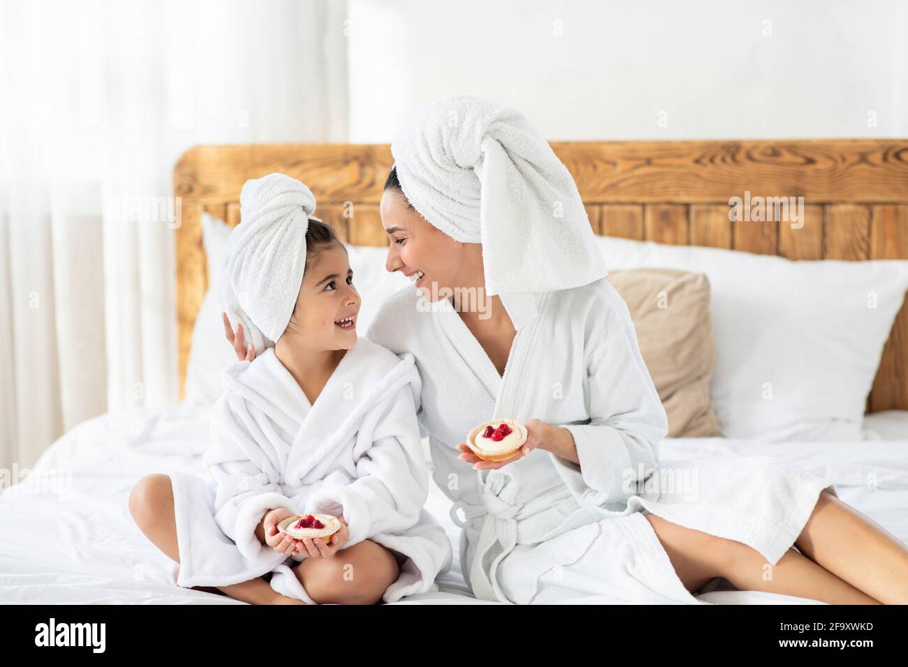 Happy mother and kid wearing bathrobes, eating pastry Stock Photo - Alamy