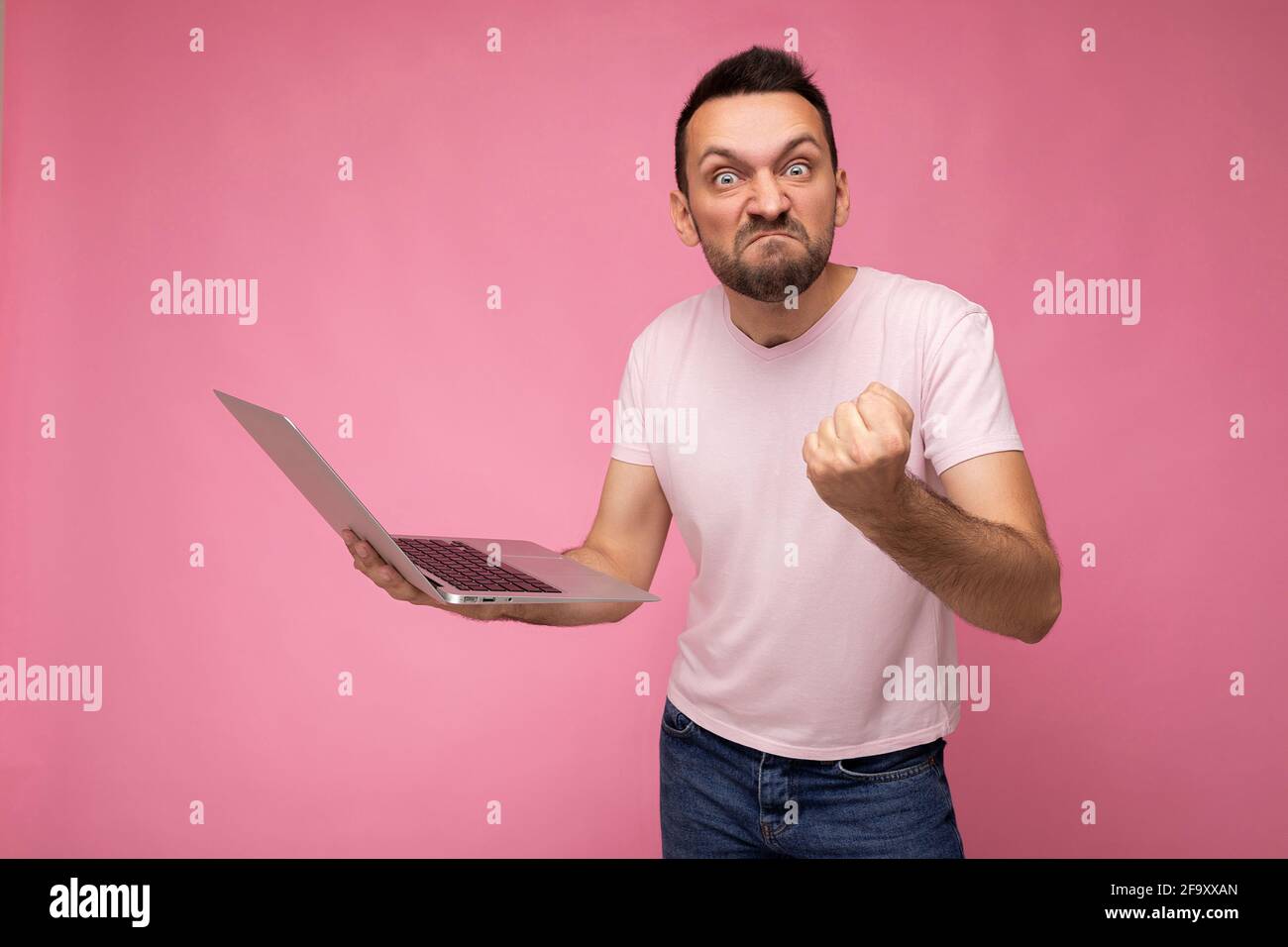 Handsome angry and wrathful man holding laptop computer showing fist ...