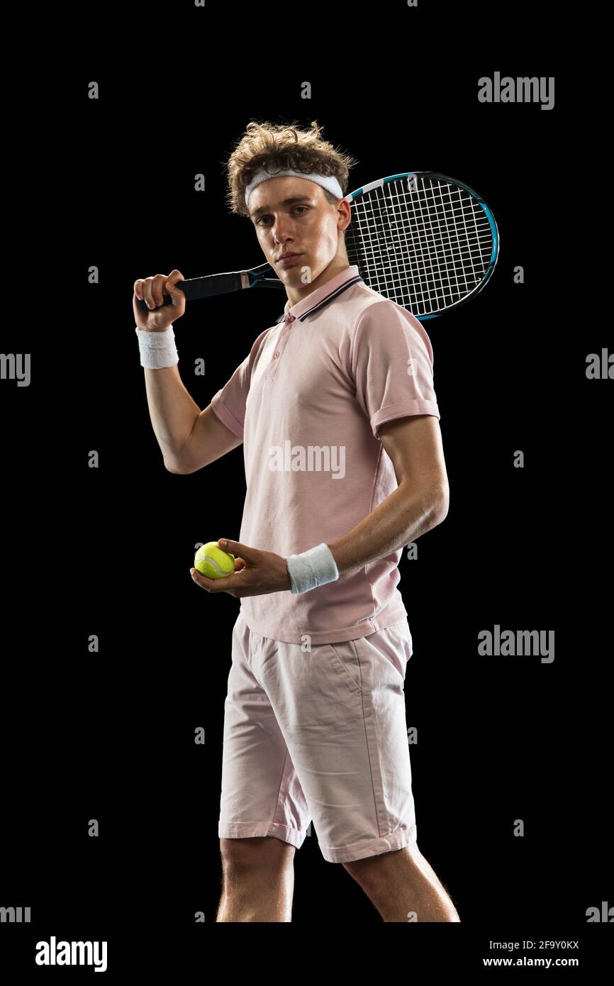 Portrait of young man, professional tennis player isolated on black ...
