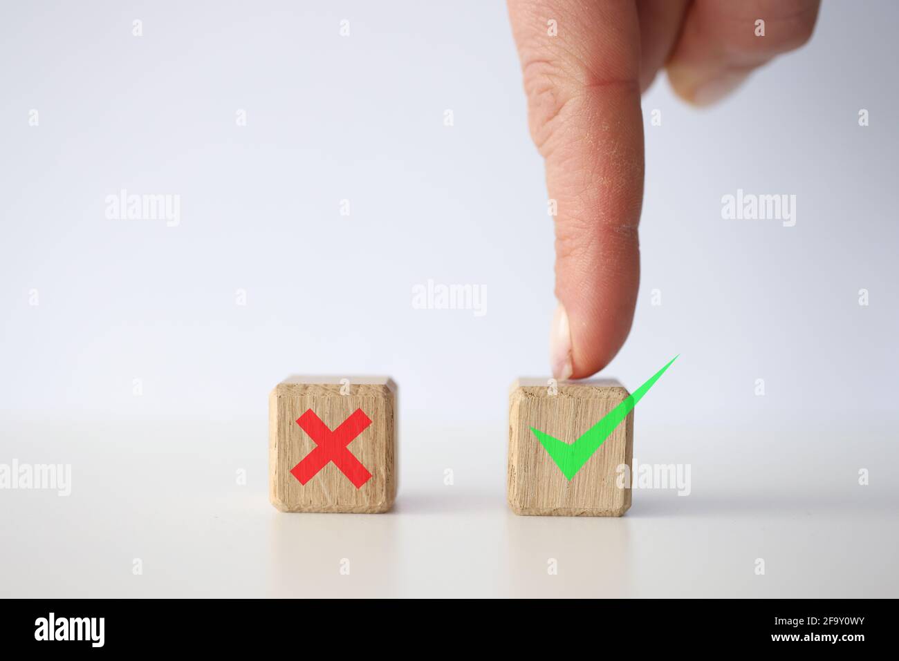 Person finger points to a cube with green check mark Stock Photo - Alamy