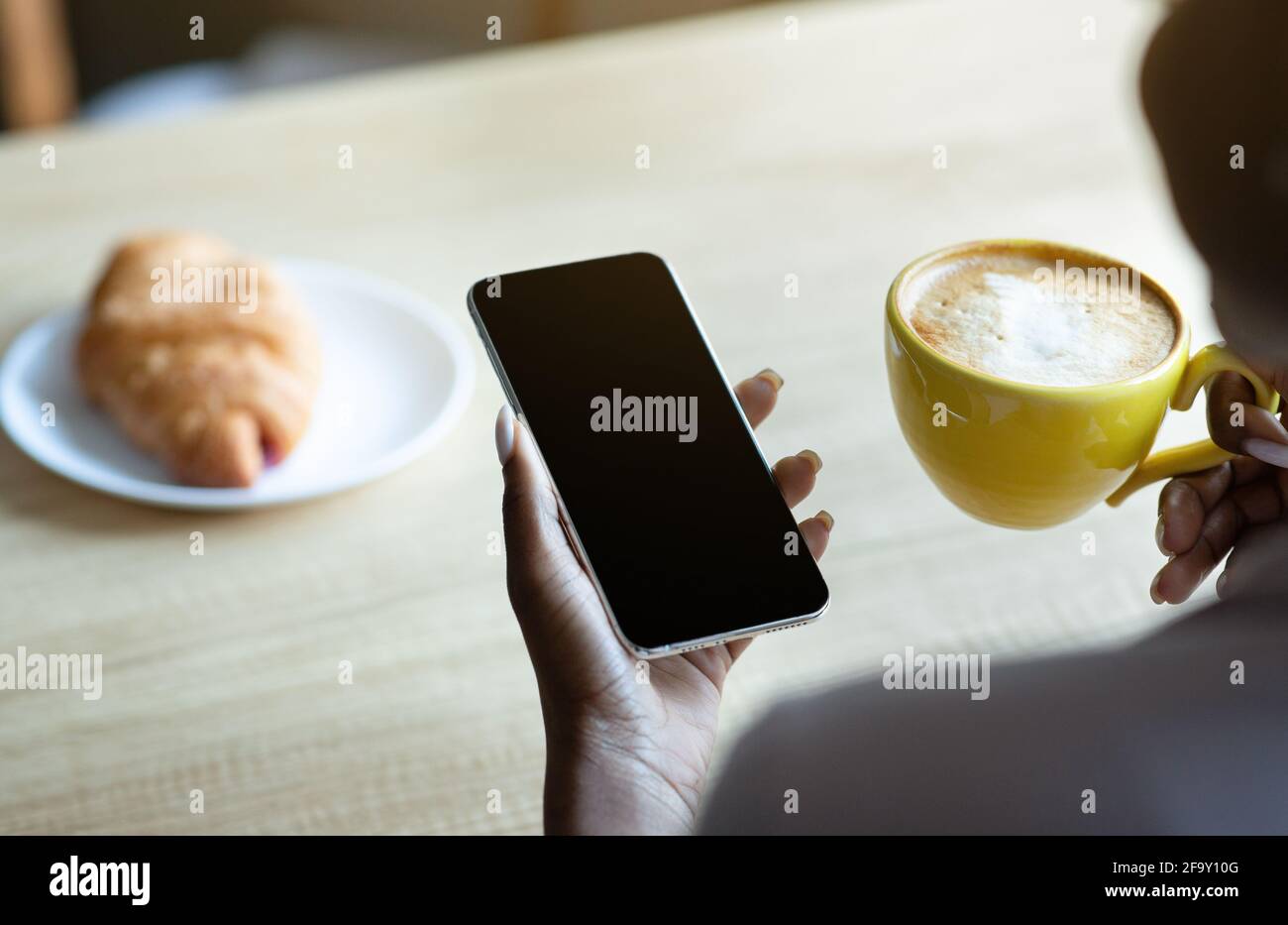 Unrecognizable black woman holding mobile phone with blank screen while ...