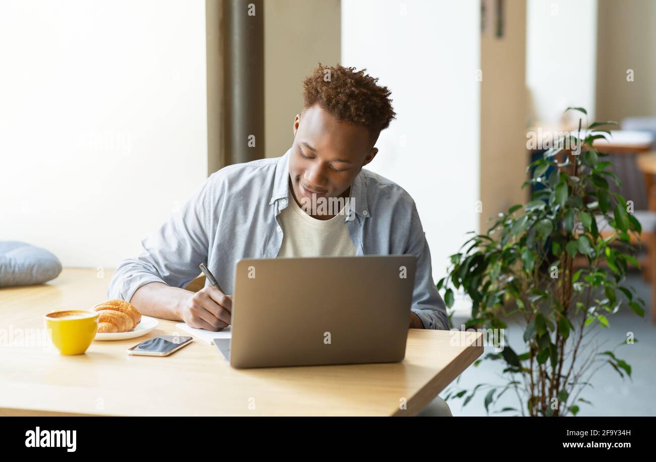 Smart black guy with laptop working on project or studying remotely ...