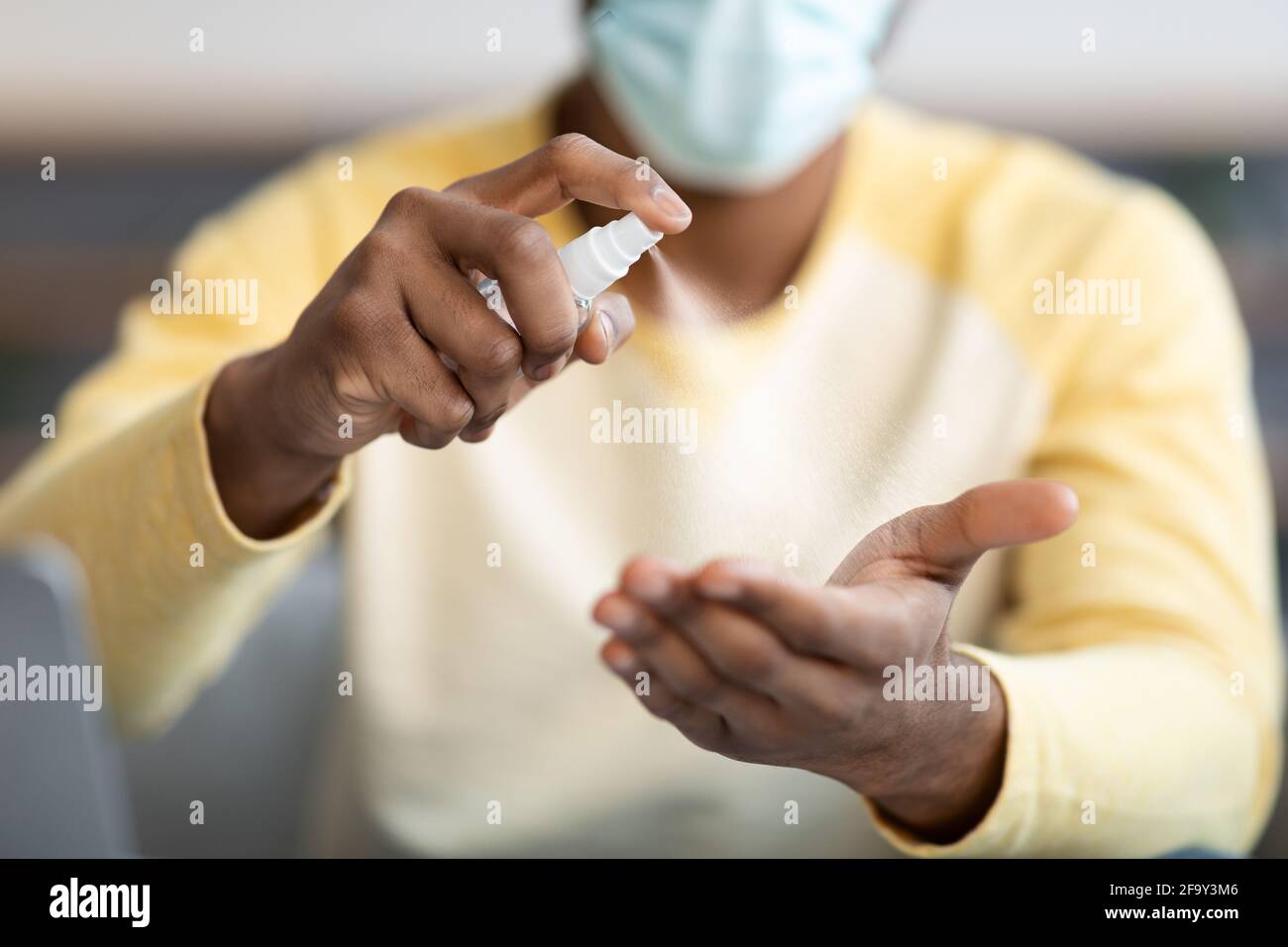 Closeup of black guy hands with disinfectant mist spray Stock Photo - Alamy