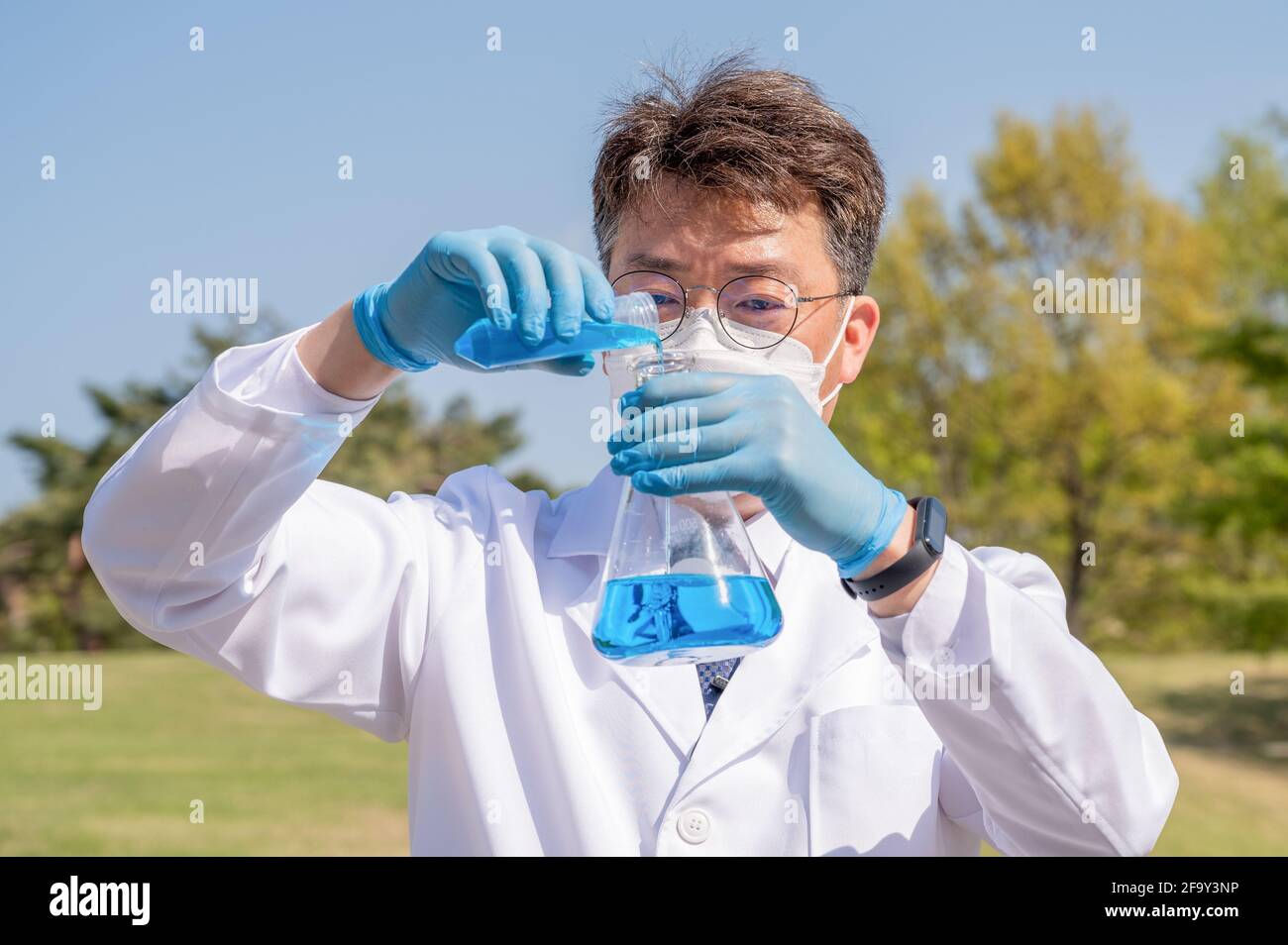Portrait of a middle-year Asian male scientist wearing a white lab gown ...