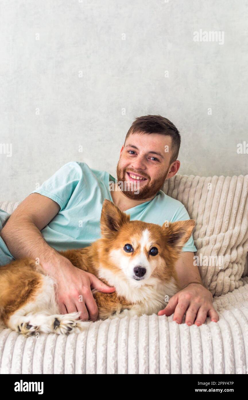 owner lies on the bed with his ginger dog hugging. Vertical photo Stock ...