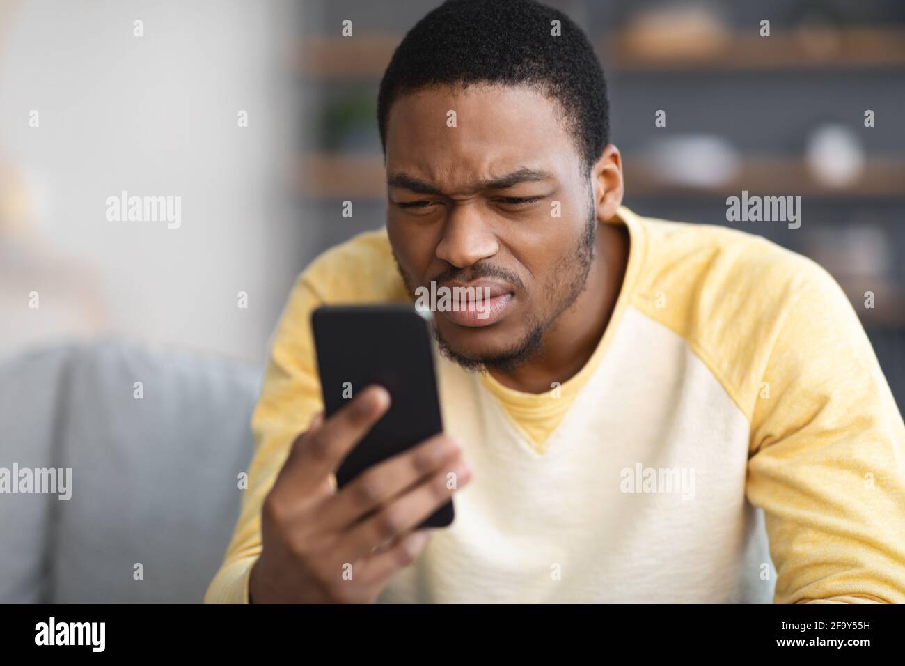 African american guy squinting while using mobile phone Stock Photo - Alamy
