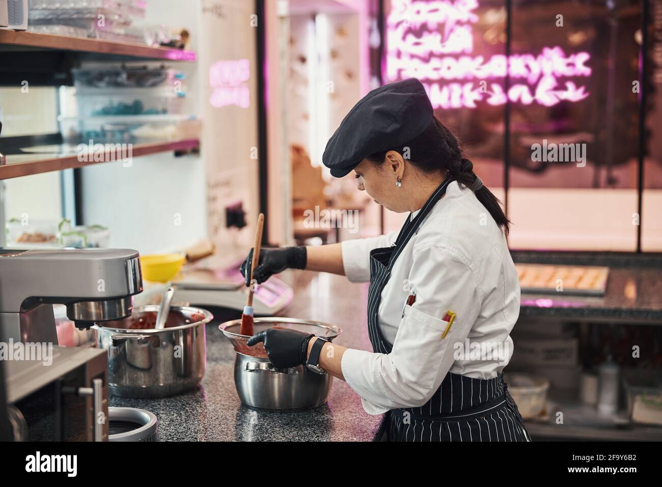 Concentrated female cook using wooden spatula for stirring Stock Photo ...
