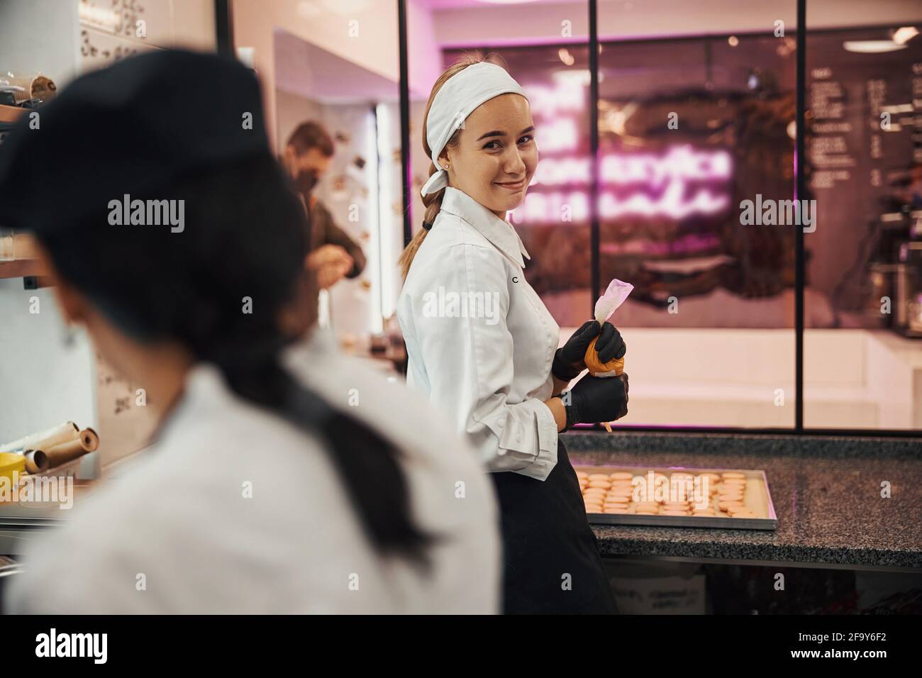 Friendly female chef posing with syringe full of icing Stock Photo - Alamy
