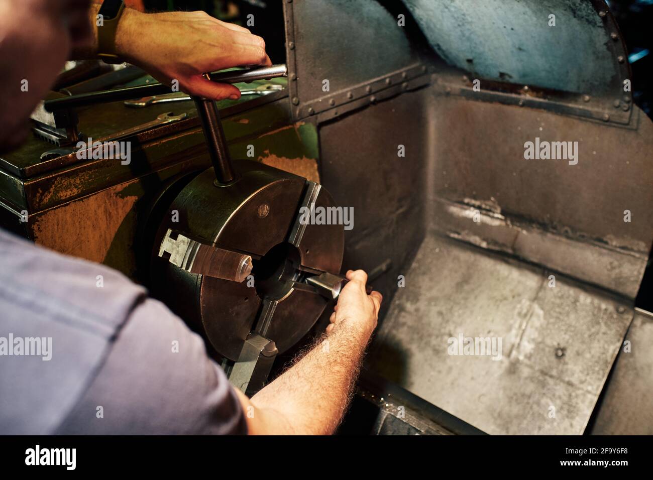 Closeup shot of a Hispanic mechanical engineer controlling the lathe ...