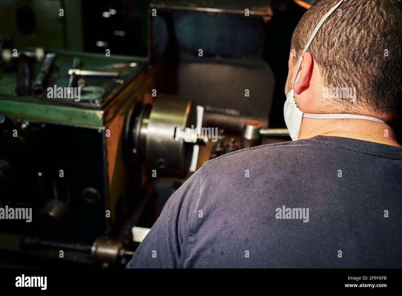 Closeup shot of a Hispanic mechanical engineer controlling the lathe ...