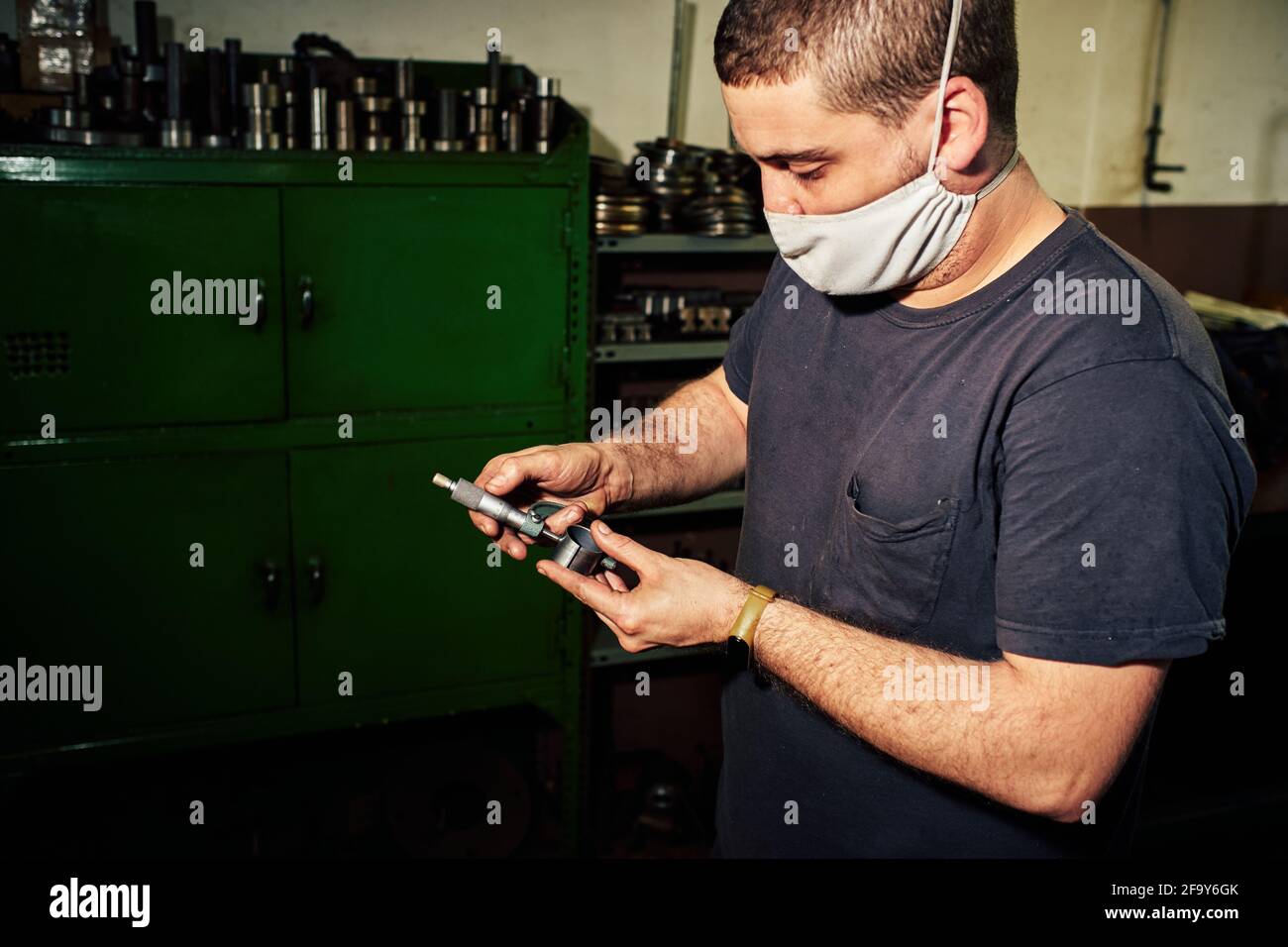 Closeup shot of a Hispanic mechanical engineer controlling the lathe ...