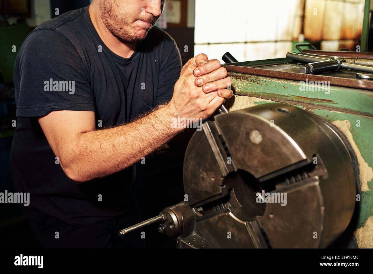 Closeup shot of a Hispanic mechanical engineer controlling the lathe ...