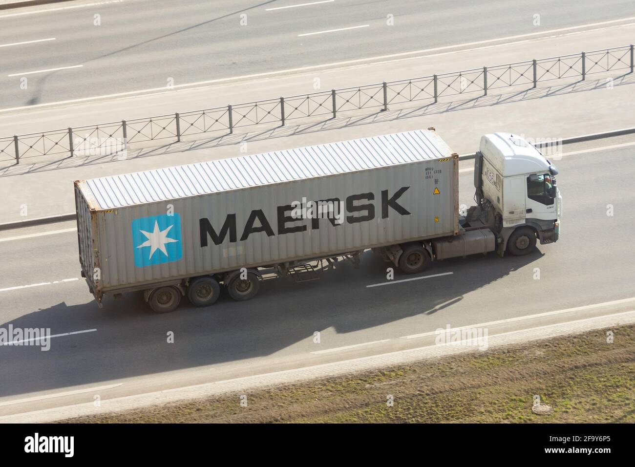 Truck with trailer and green container company Maersk on city highway ...