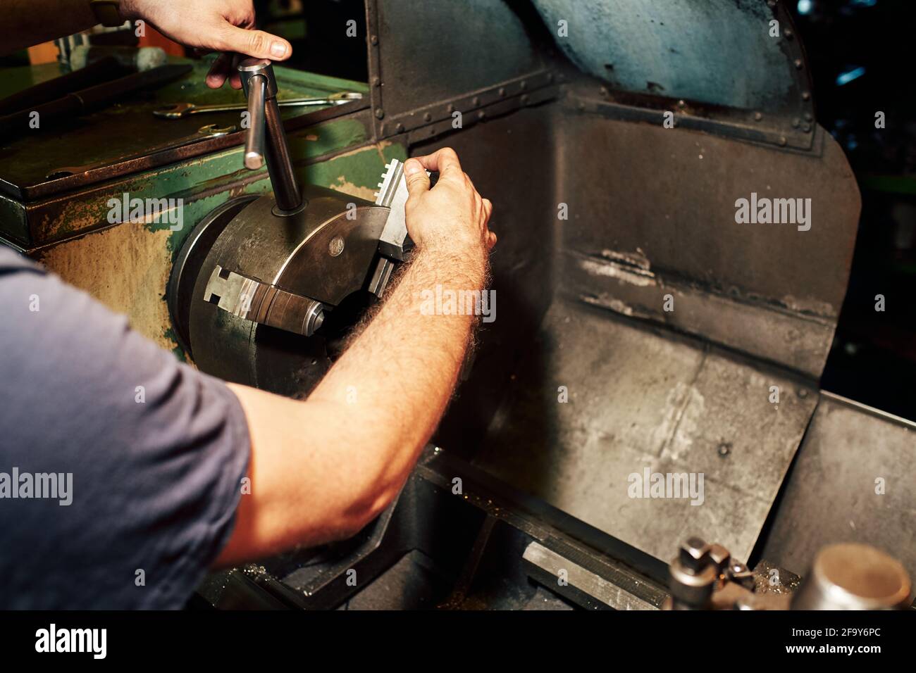 Closeup shot of a Hispanic mechanical engineer controlling the lathe ...