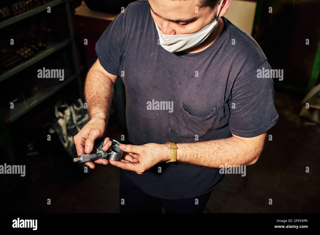 Closeup shot of a Hispanic mechanical engineer controlling the lathe ...
