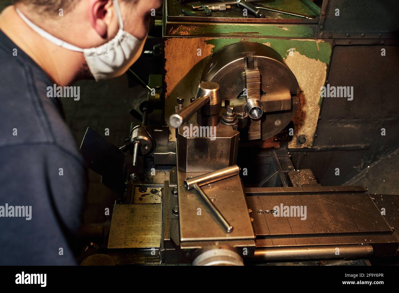 Closeup shot of a Hispanic mechanical engineer controlling the lathe ...