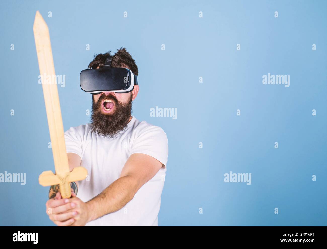 VR gamer concept. Guy with head mounted display and sword play fighting ...