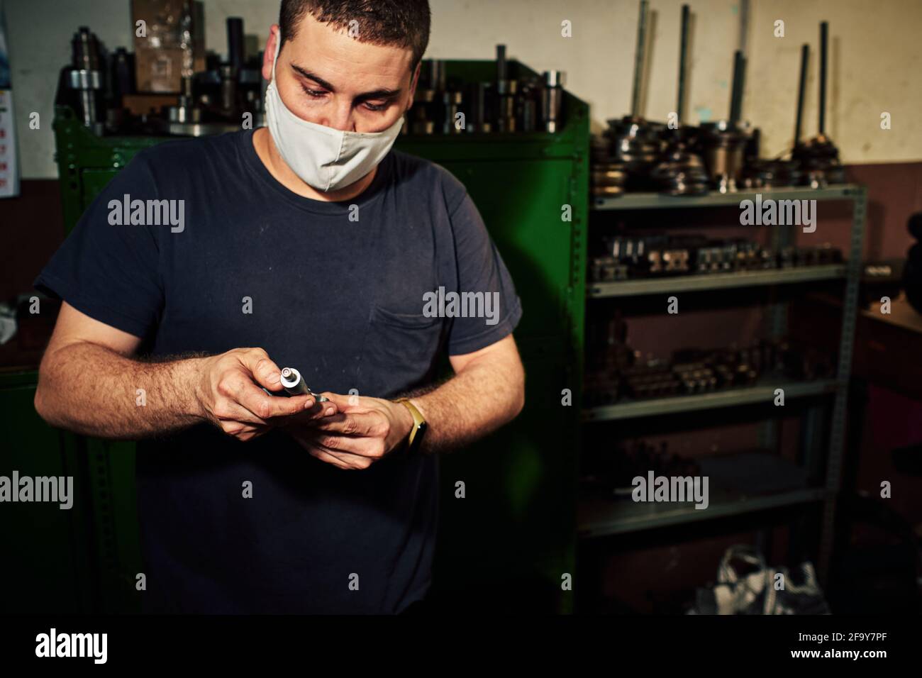 Closeup shot of a Hispanic mechanical engineer controlling the lathe ...
