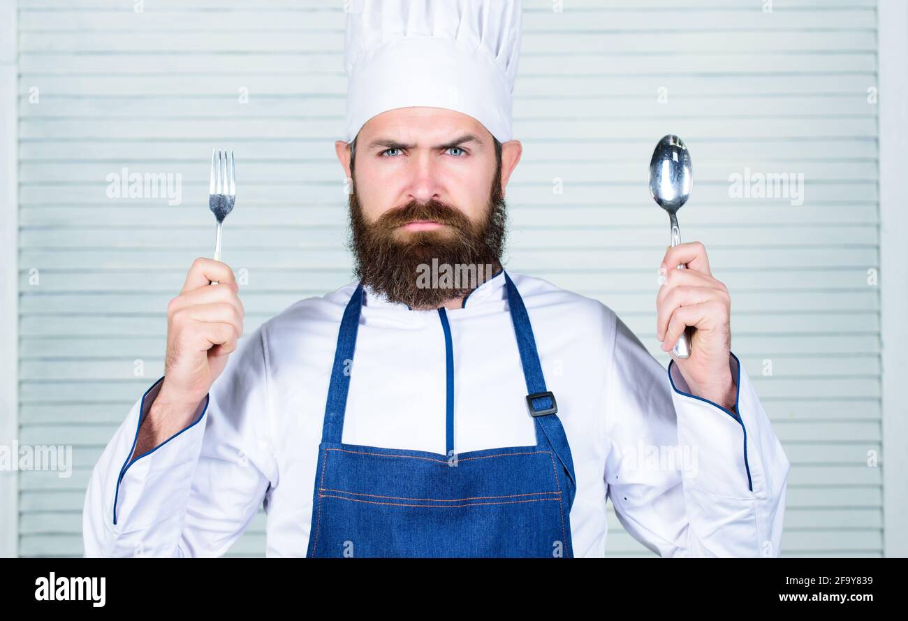 Time to try taste. Chef serious face hold spoon and fork. Man handsome ...