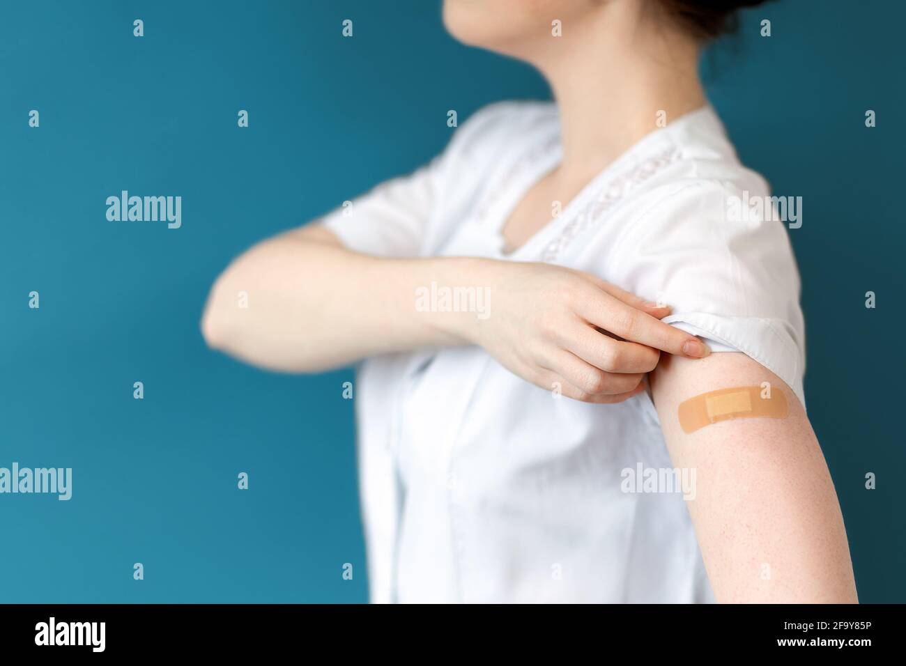 Coronavirus vaccination. Nurse shows a hand with a band-aid stuck on it ...