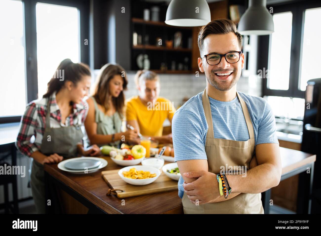 Group of happy friends having fun in kitchen, cooking food together ...