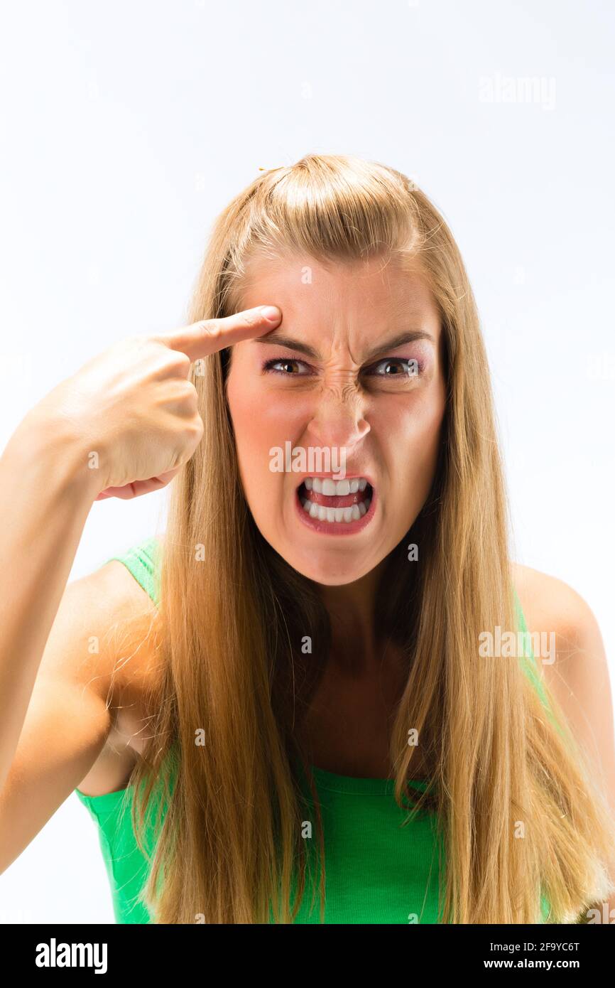 Close-up of an aggressive young woman clenching her teeth against white ...