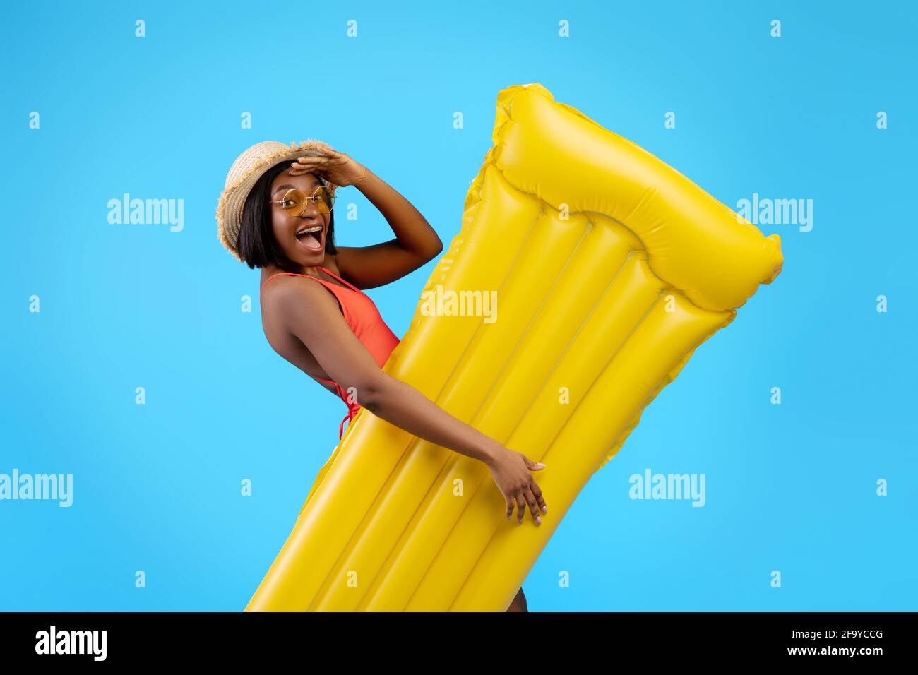 Millennial black woman in swimsuit holding yellow inflatable lilo on ...