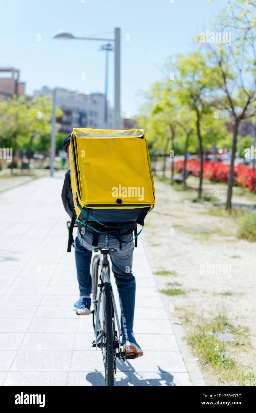 A rear view of male bicycle courier delivering packages in city Stock ...