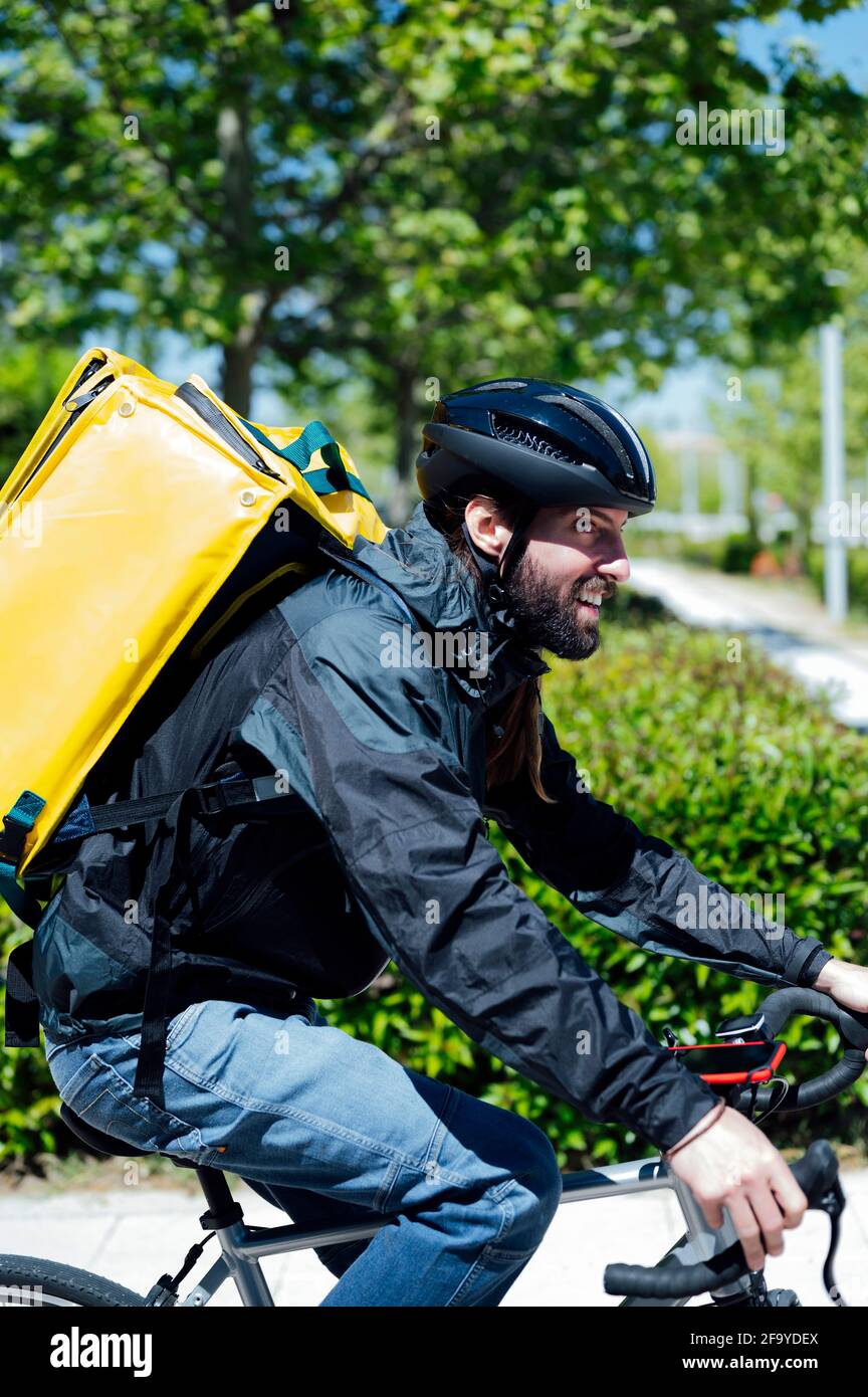 delivery man with yellow backpack riding a bicycle Stock Photo - Alamy