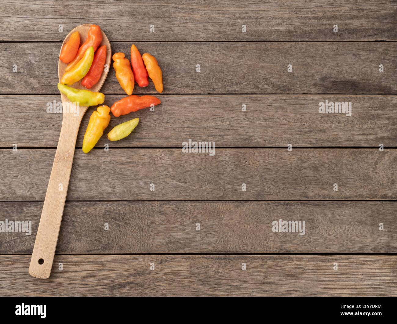 Orange cheiro (smell,scent) peppers on a spoon over wooden table with ...