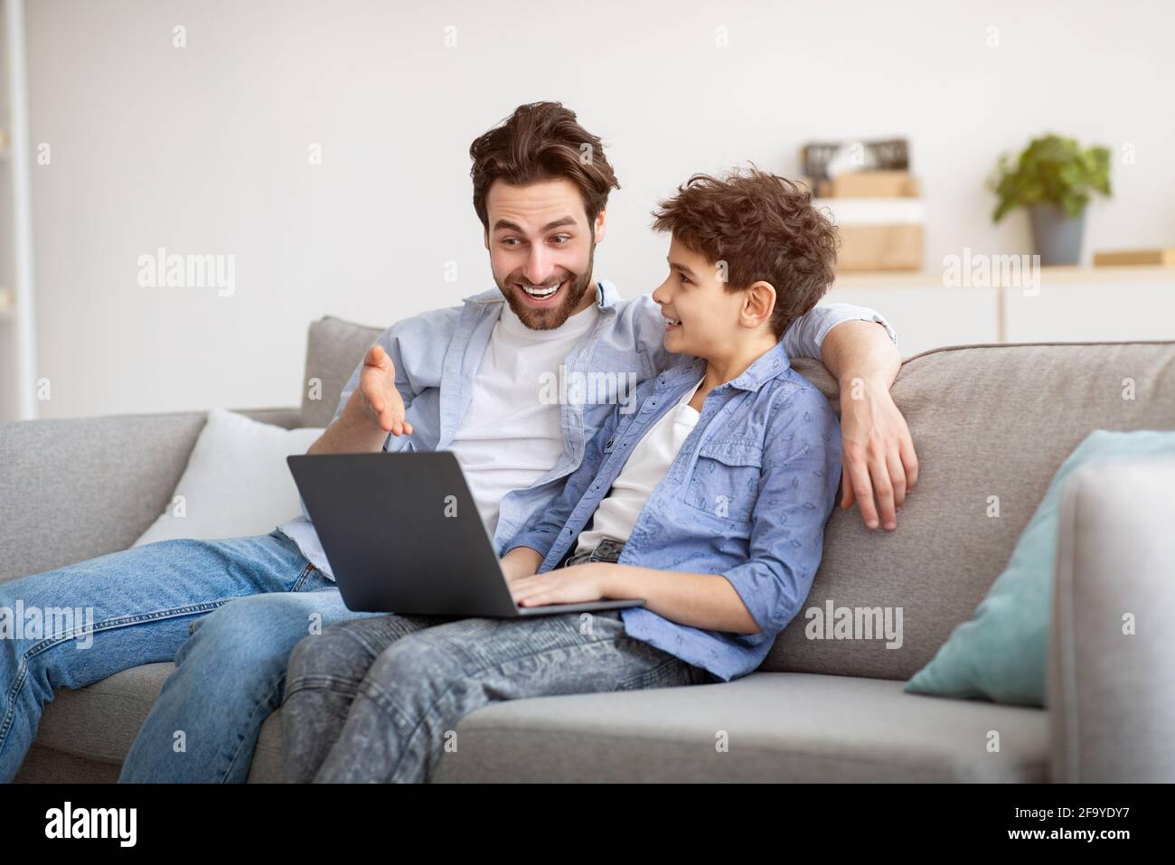 Emotional dad and his son using laptop together, making online shopping ...
