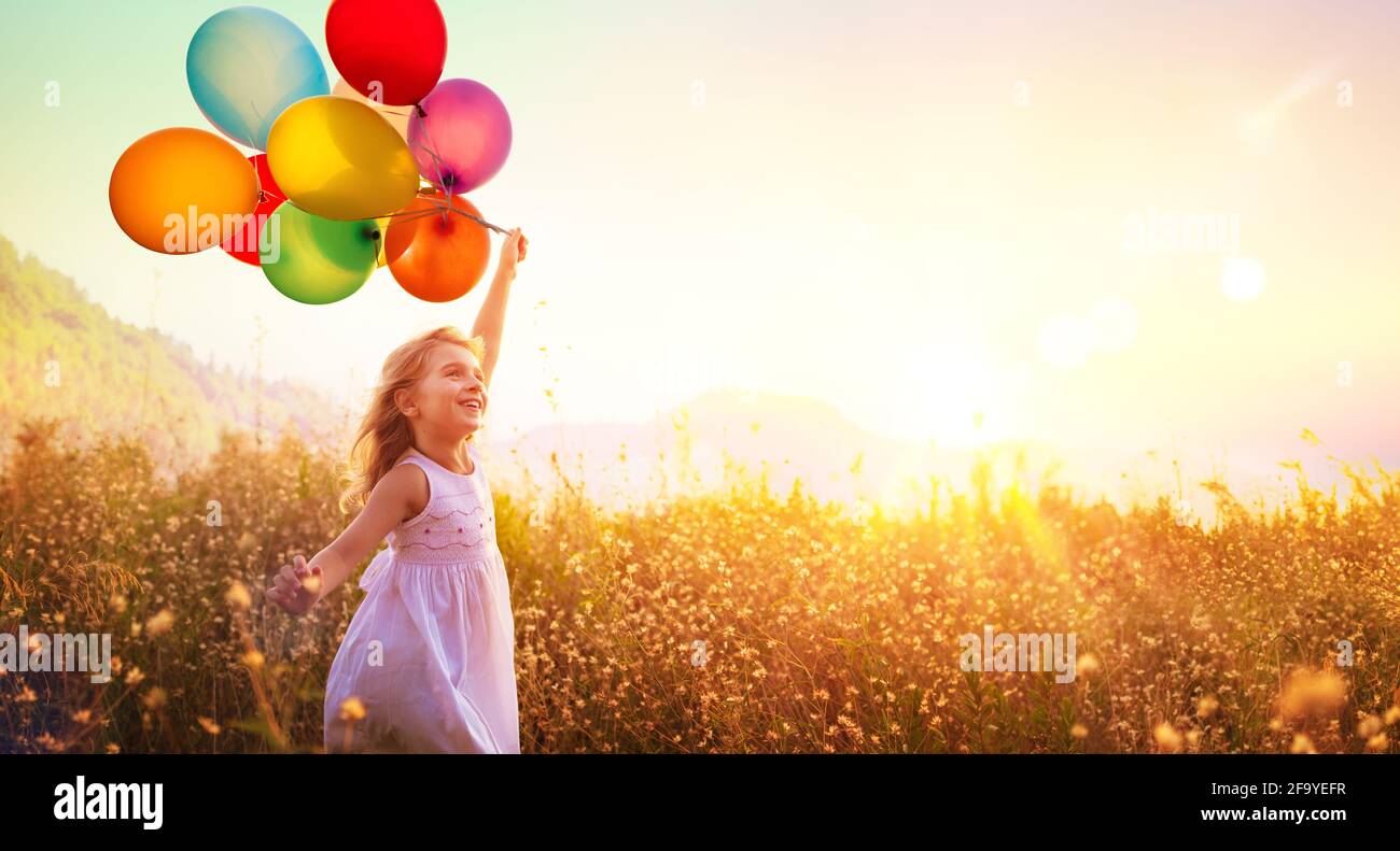 Happy Child Running With Balloons In Field At Sunset Stock Photo - Alamy