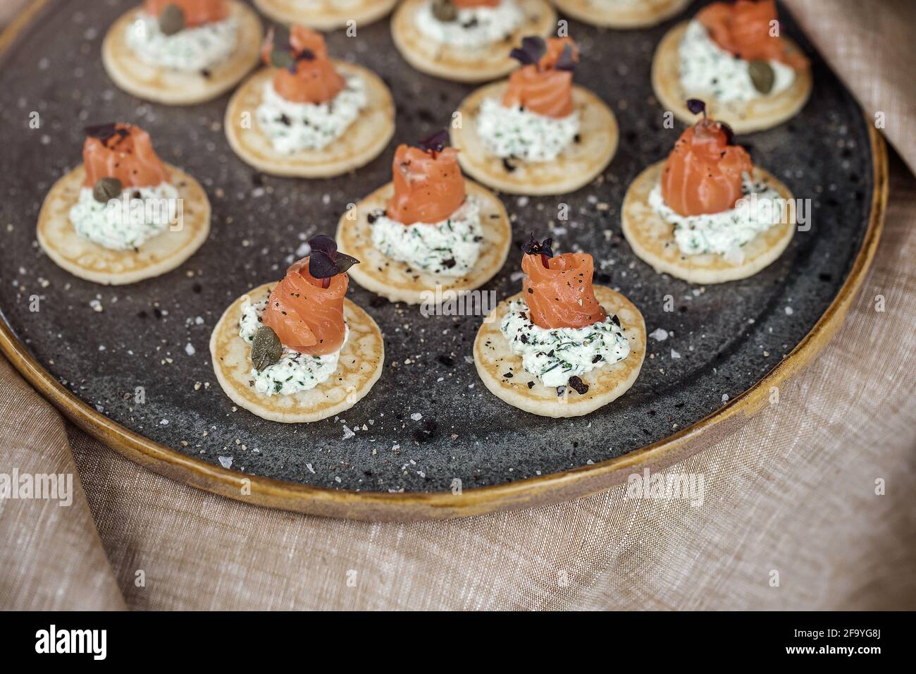Handmade craft plate and salmon one bite snack on it, on linen ...
