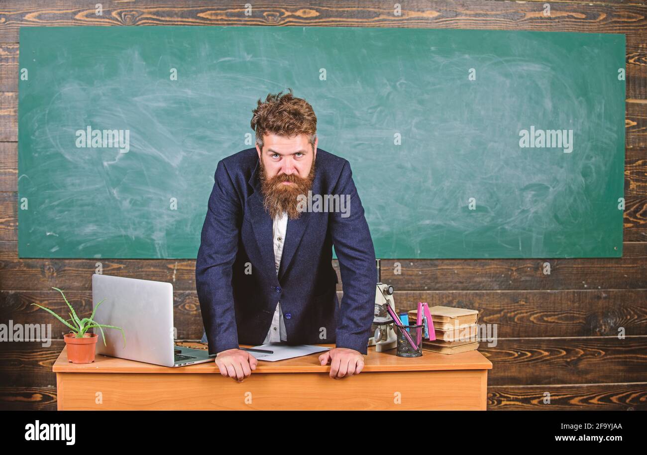 Teacher strict serious bearded man lean on table chalkboard background ...